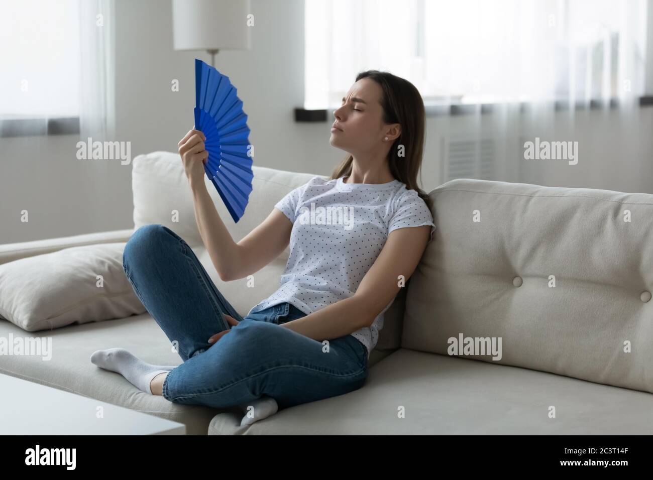Woman suffers from unbearable hot weather waving fan cooling herself ...