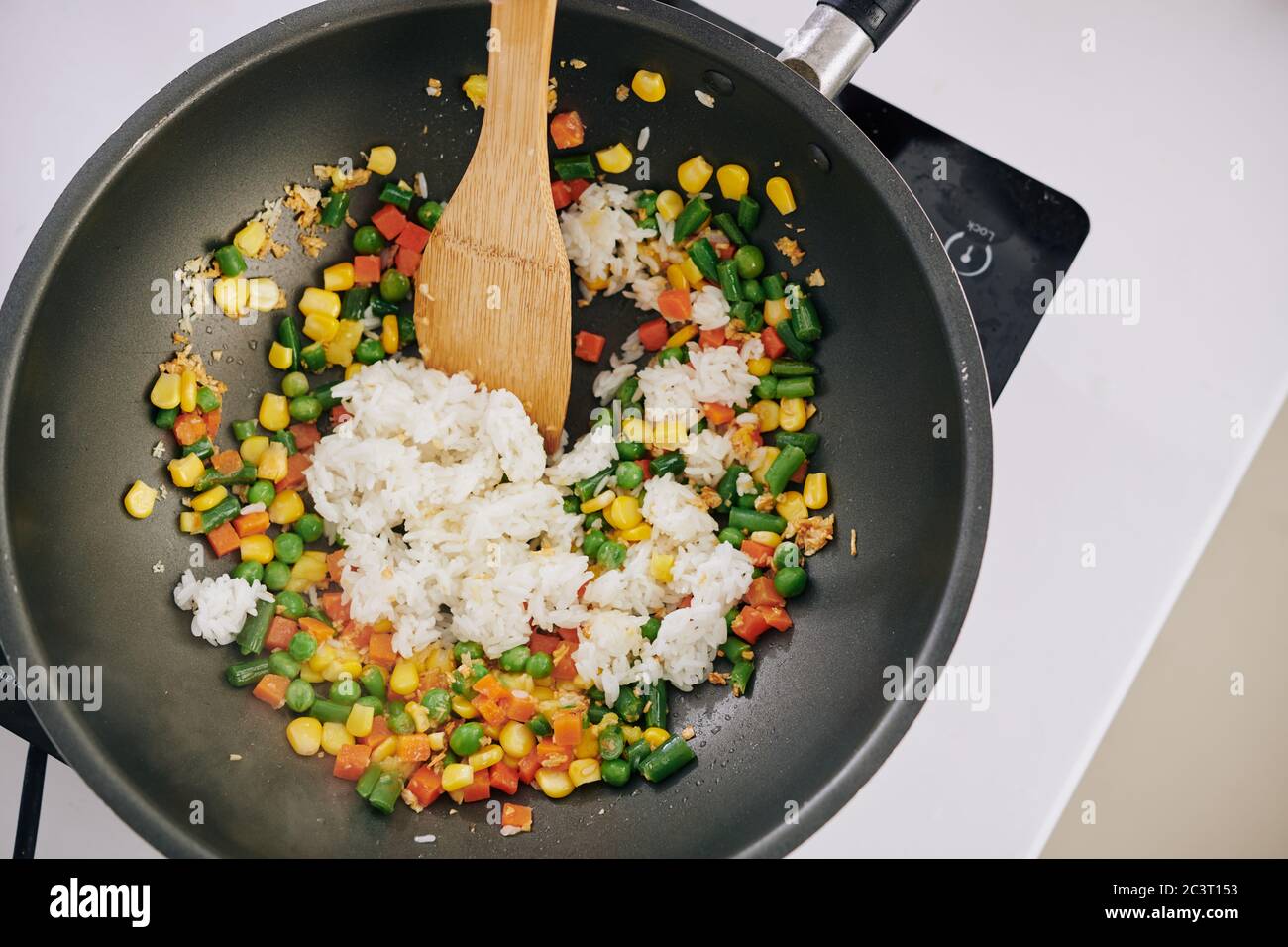 Person frying rice in cooking pan with various vegetables for the ...
