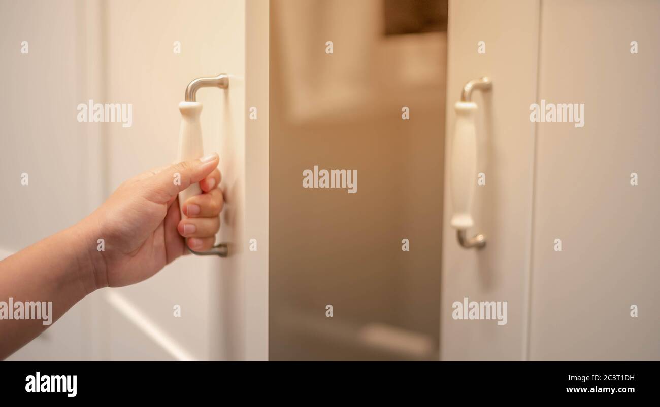 Female hand opening white wardrobe doors with the walkin closet style ...