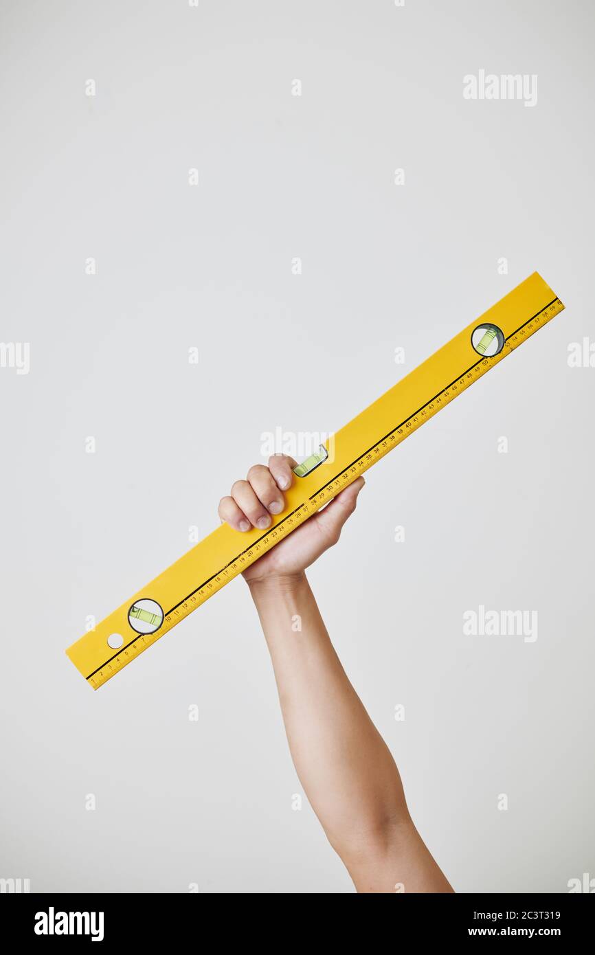 Hand of construction worker showing spirit level, isolated on grey ...