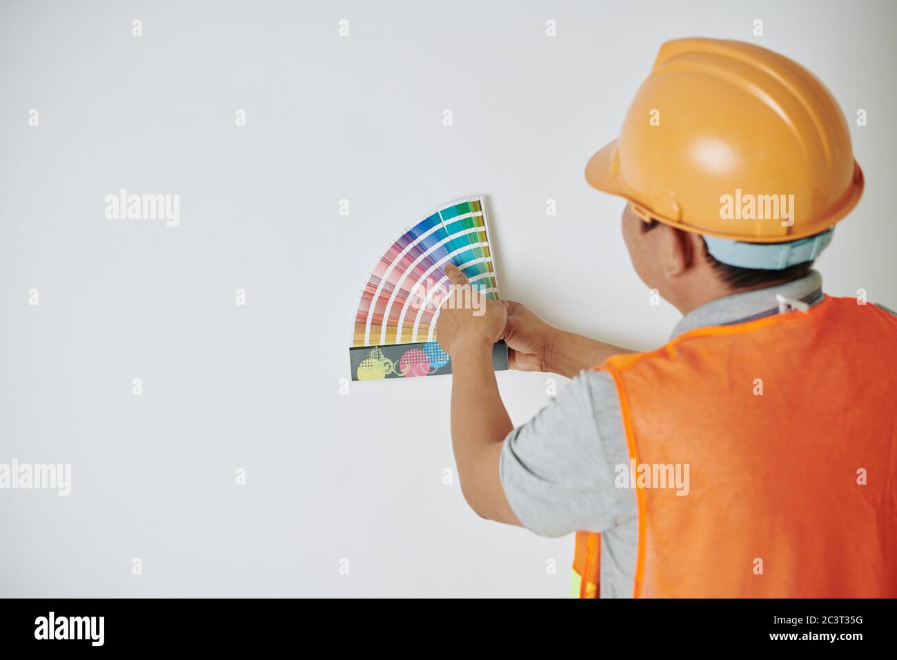 Construction worker in hardhat and orange vest choosing color from ...