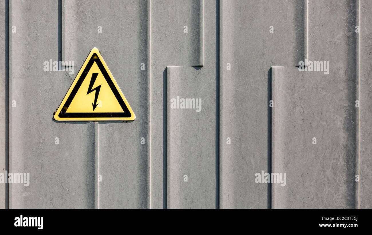Sign of high voltage on a gray metal surface. Electrical hazard symbol ...