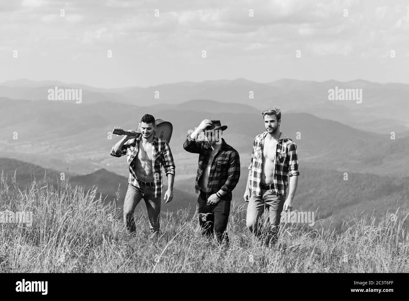 Friendly guys with guitar hiking on sunny day. Tourists hiking concept ...