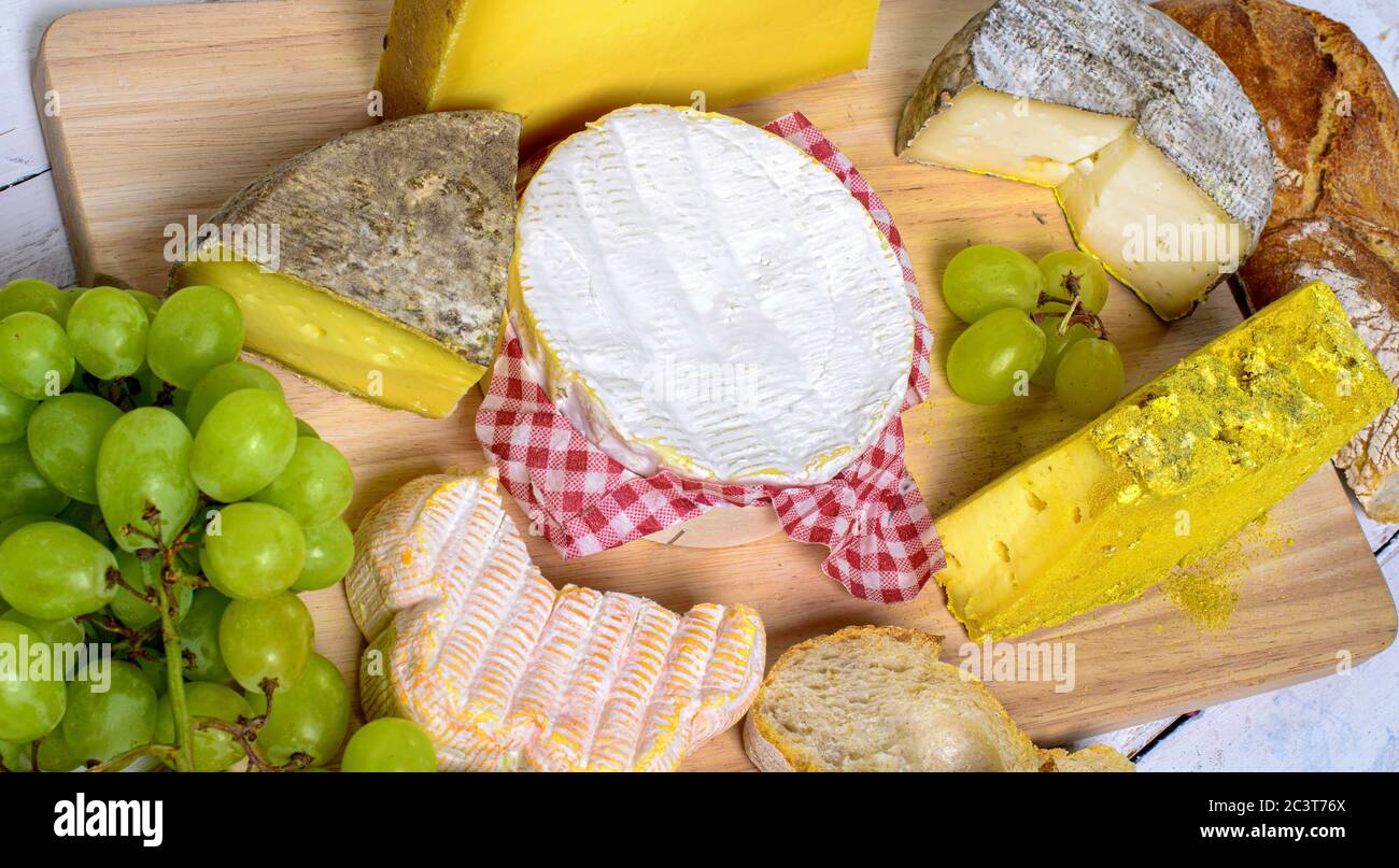 assortment of french cheeses, camembert, tome, st albray and grapes ...