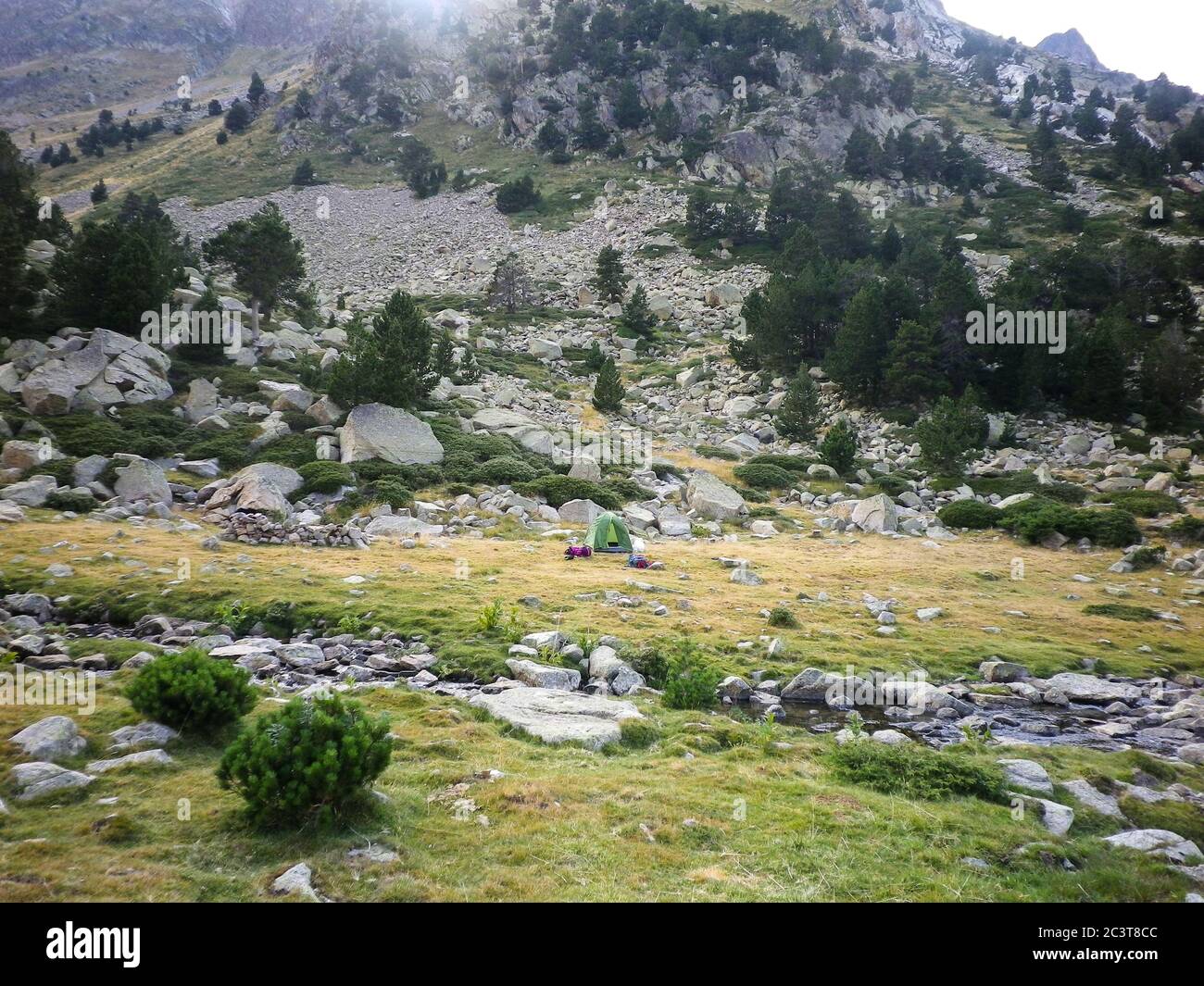 A tent in the middle of a high mountain valley with a small river ...