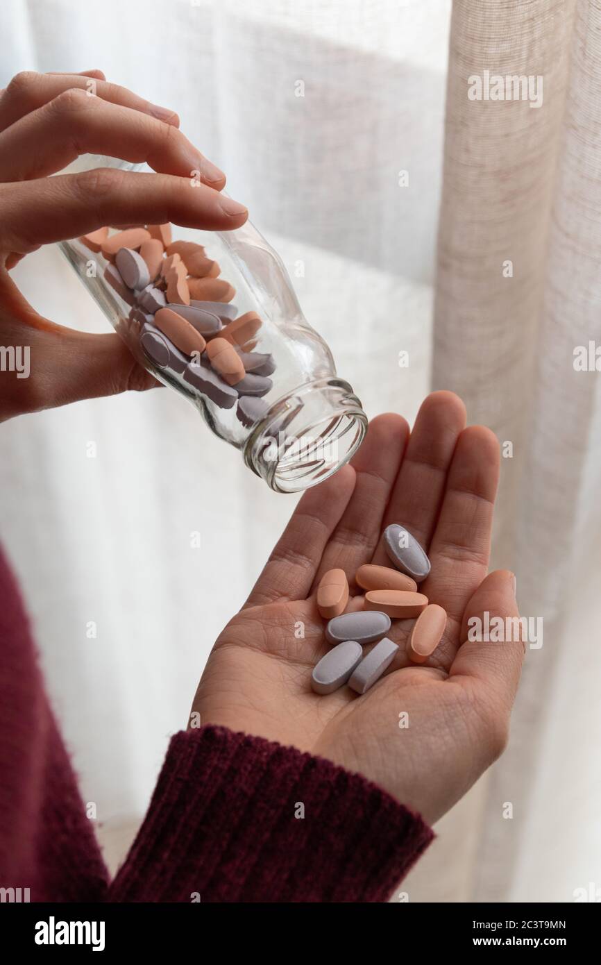 Close-up of woman's hands with a bottle of pills and some pills in her ...