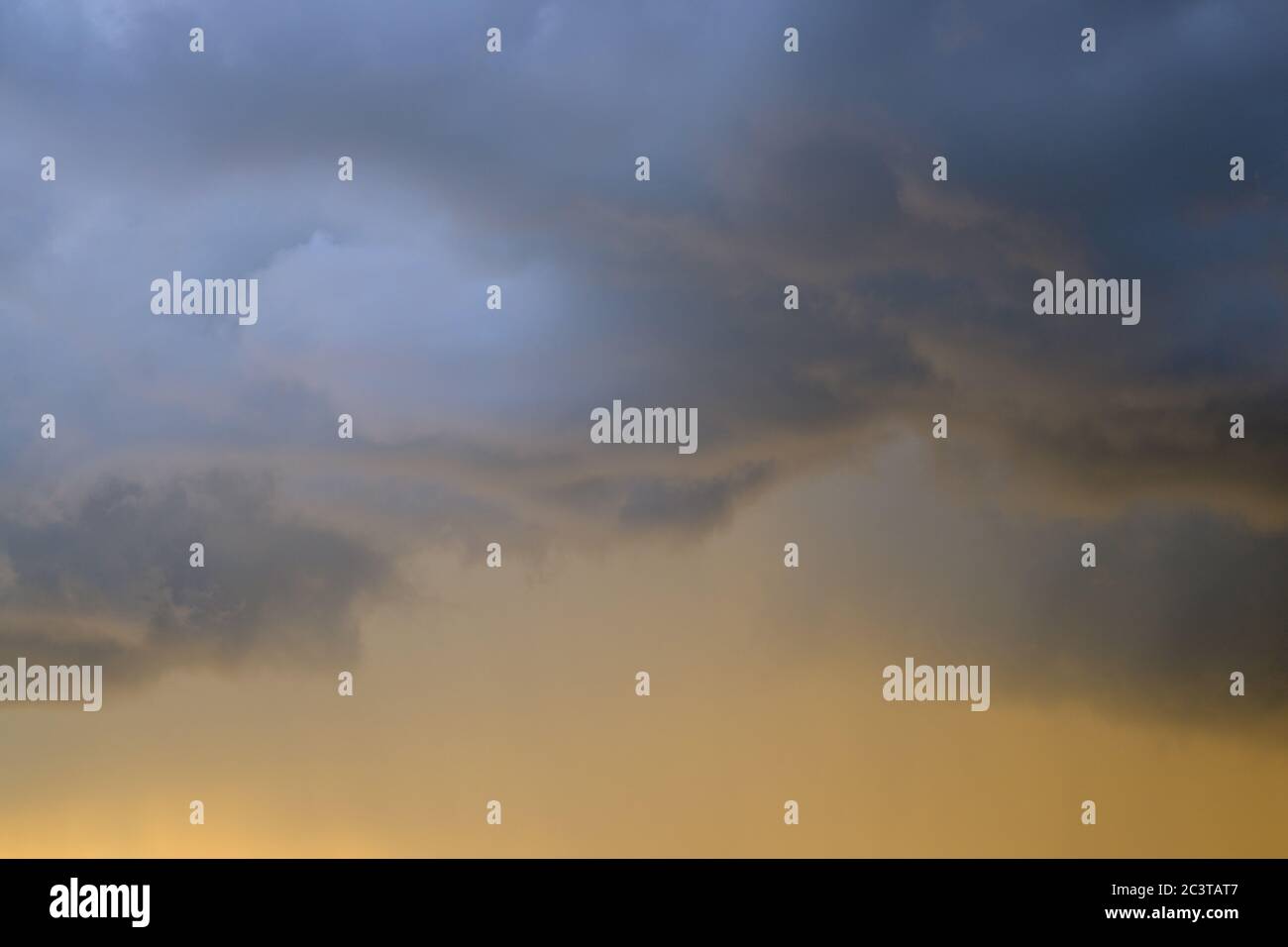 Diffuse orange sunset in a cloud sky with grey clouds in a full frame ...