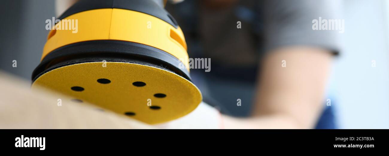 Male handy man hold yellow grinder with disc sander in hand closeup ...