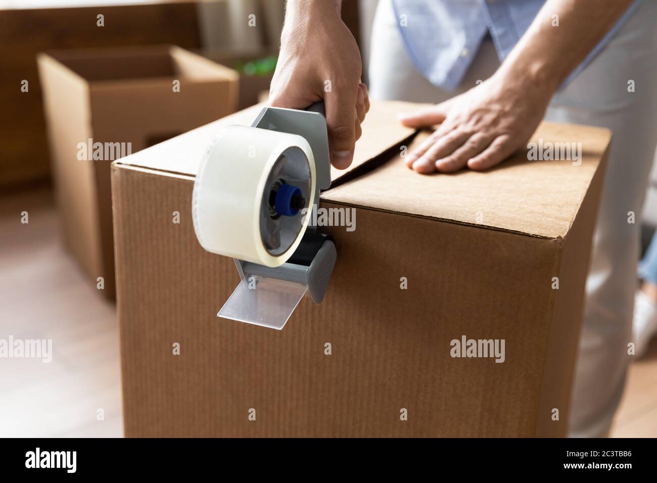 Close up man sealing cardboard box with adhesive tape Stock Photo - Alamy