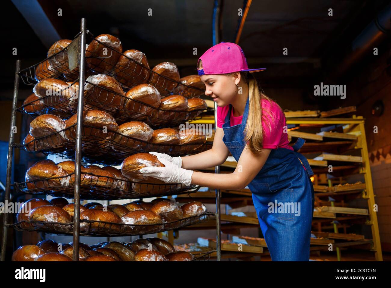 Professional baker - a young, pretty woman in a jeans apron holds fresh ...