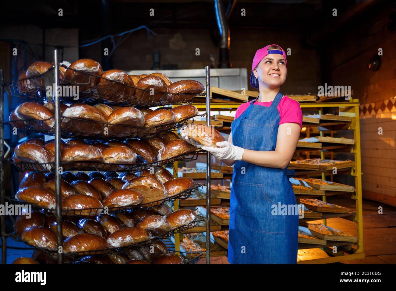 Professional baker - a young, pretty woman in a jeans apron holds fresh ...
