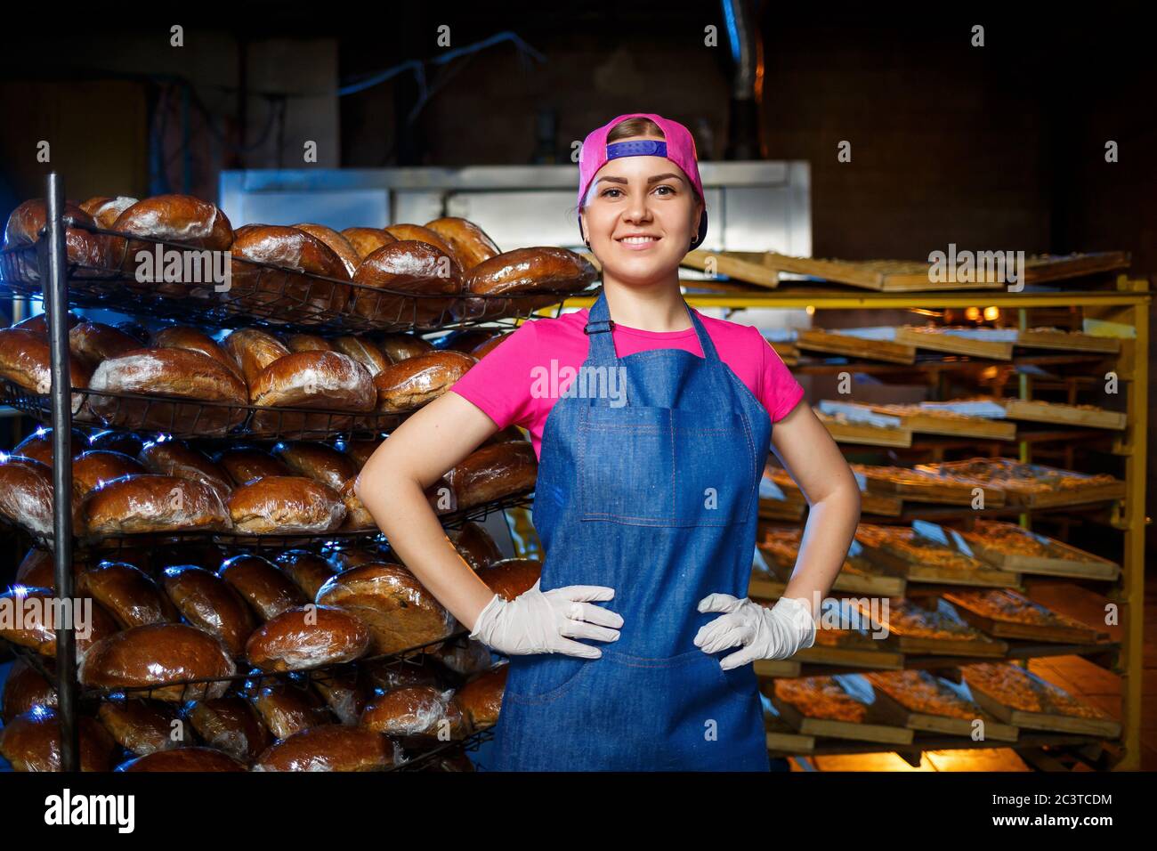 Portrait of a baker girl against the background of shelves with fresh ...