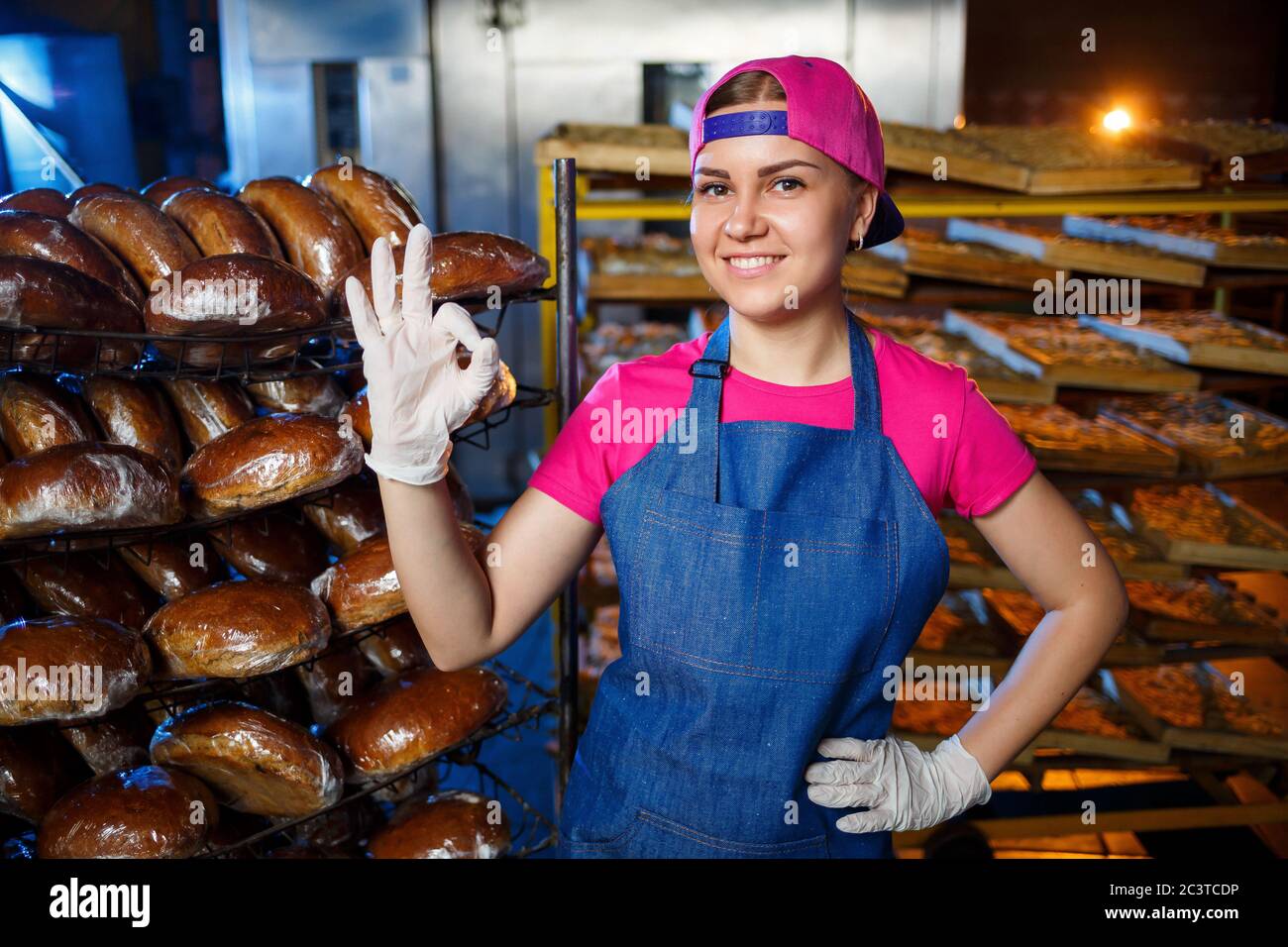 Portrait of a baker girl against the background of shelves with fresh ...
