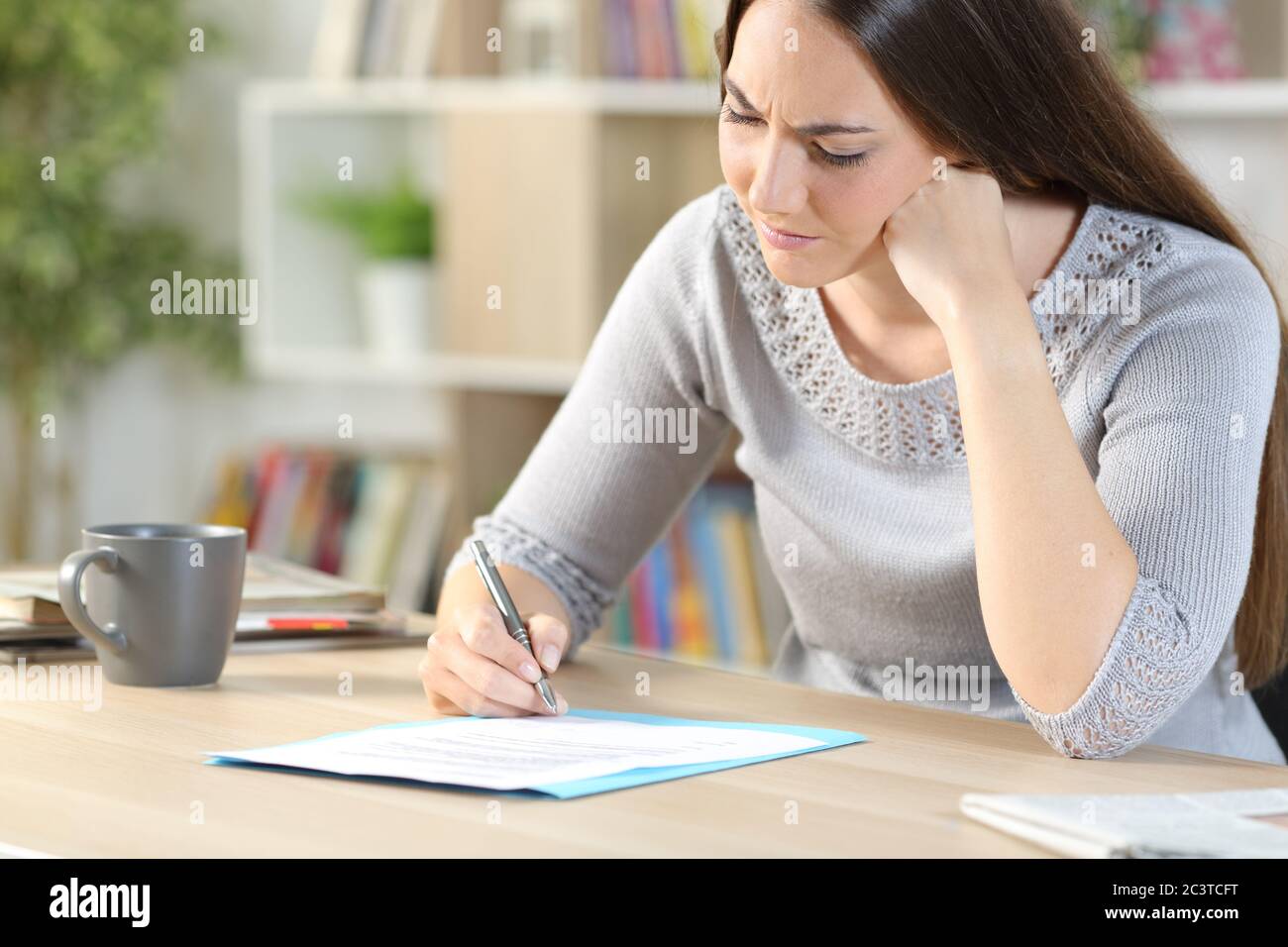 Confused woman checking and signing contract looking hesitant sitting ...
