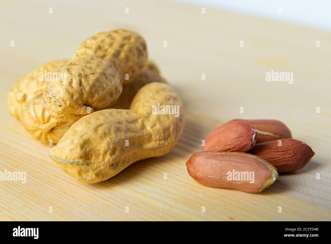 Peanuts with and without shell, on wooden surface Peanuts with and ...