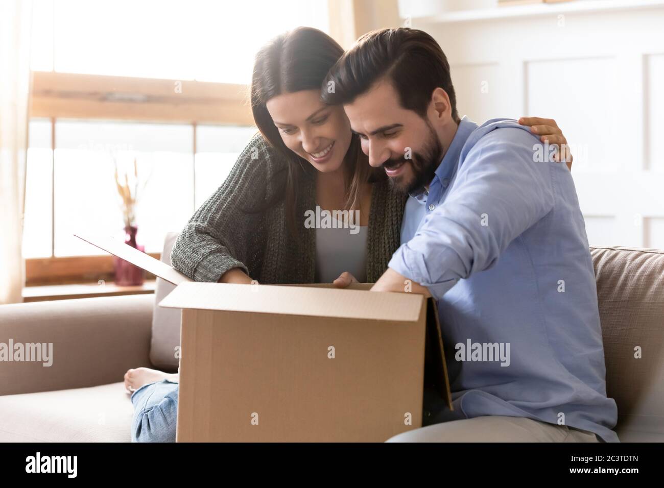 Curious young couple unpacking cardboard parcel package together Stock ...