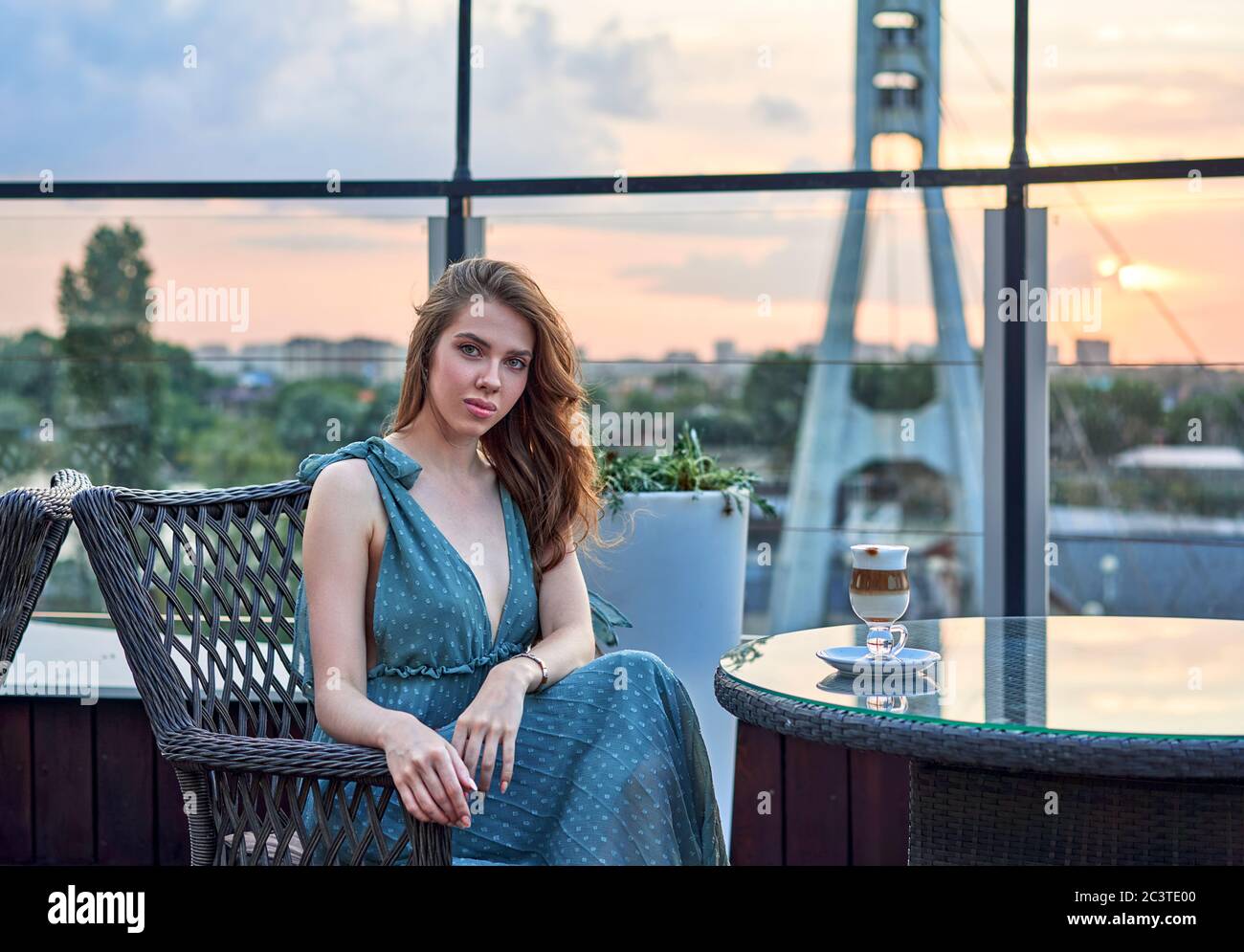 a girl in a dress is sitting on the summer veranda of a cafe Stock ...