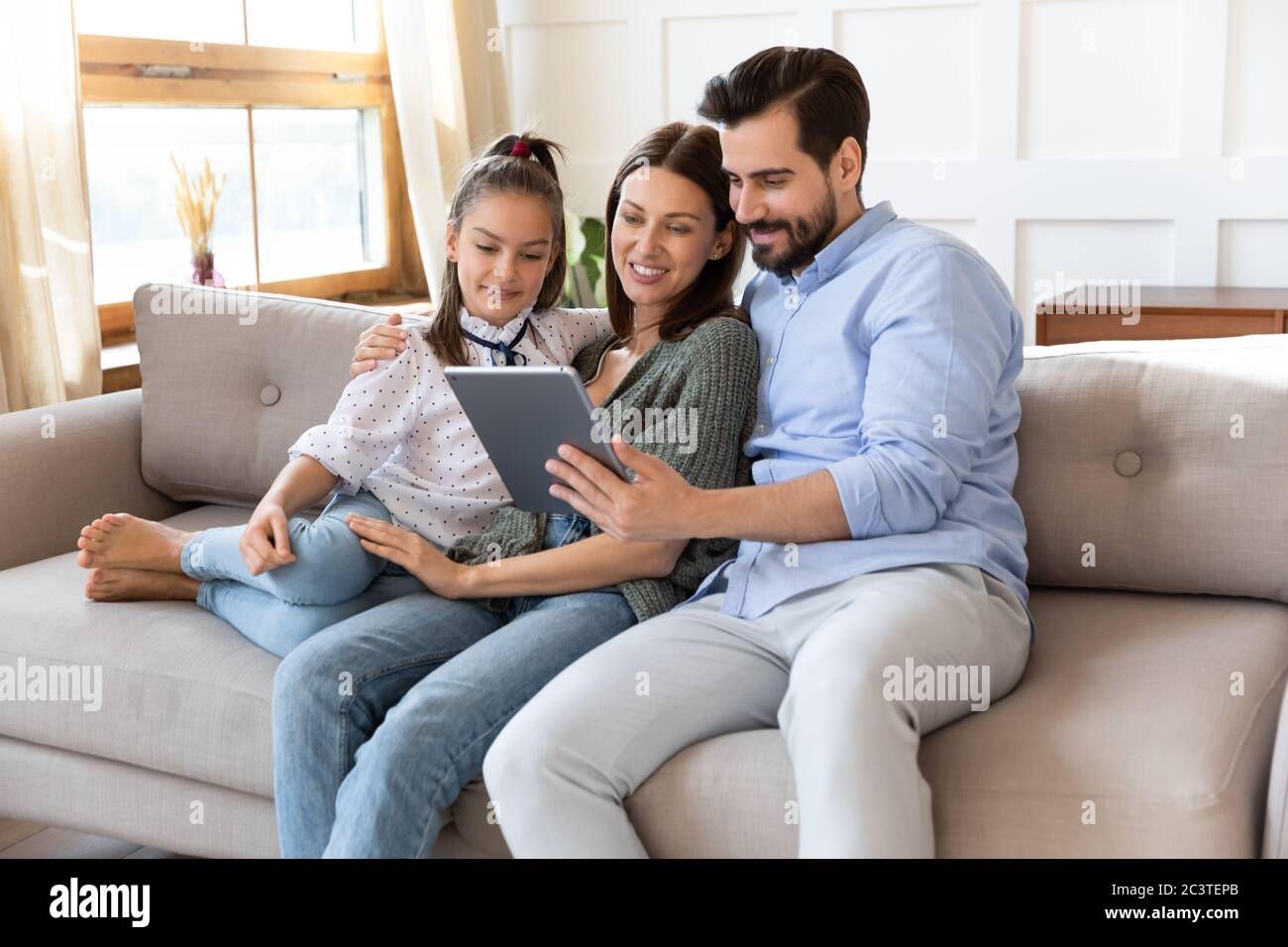 Happy parents with adorable daughter using computer tablet together ...