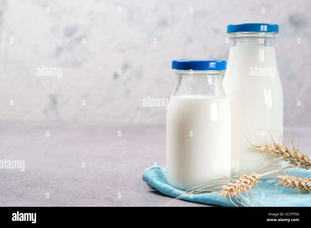 Two bottles of fresh skimmed milk with blue caps and blue towel on a ...