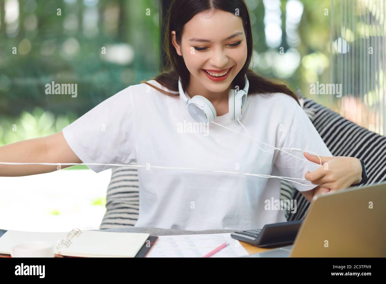 Asian woman student sitting at the table in living room, using computer ...
