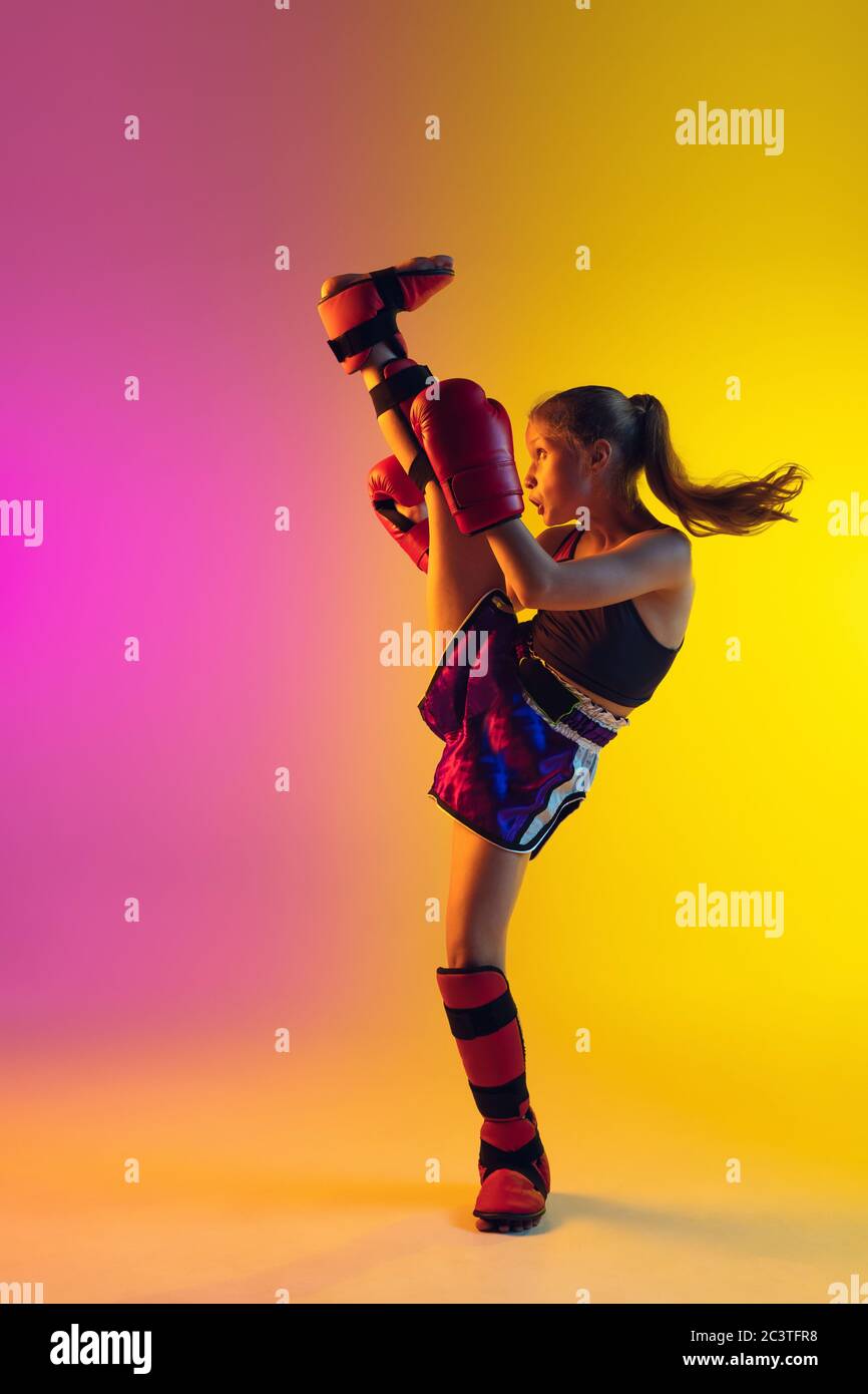 Little caucasian girl, kick boxer on gradient background in neon light ...