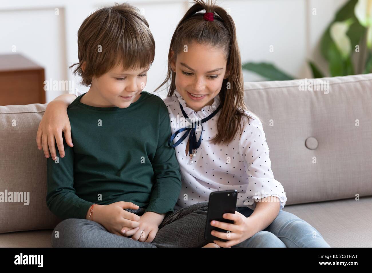Happy little sister and brother using smartphone together at home Stock ...