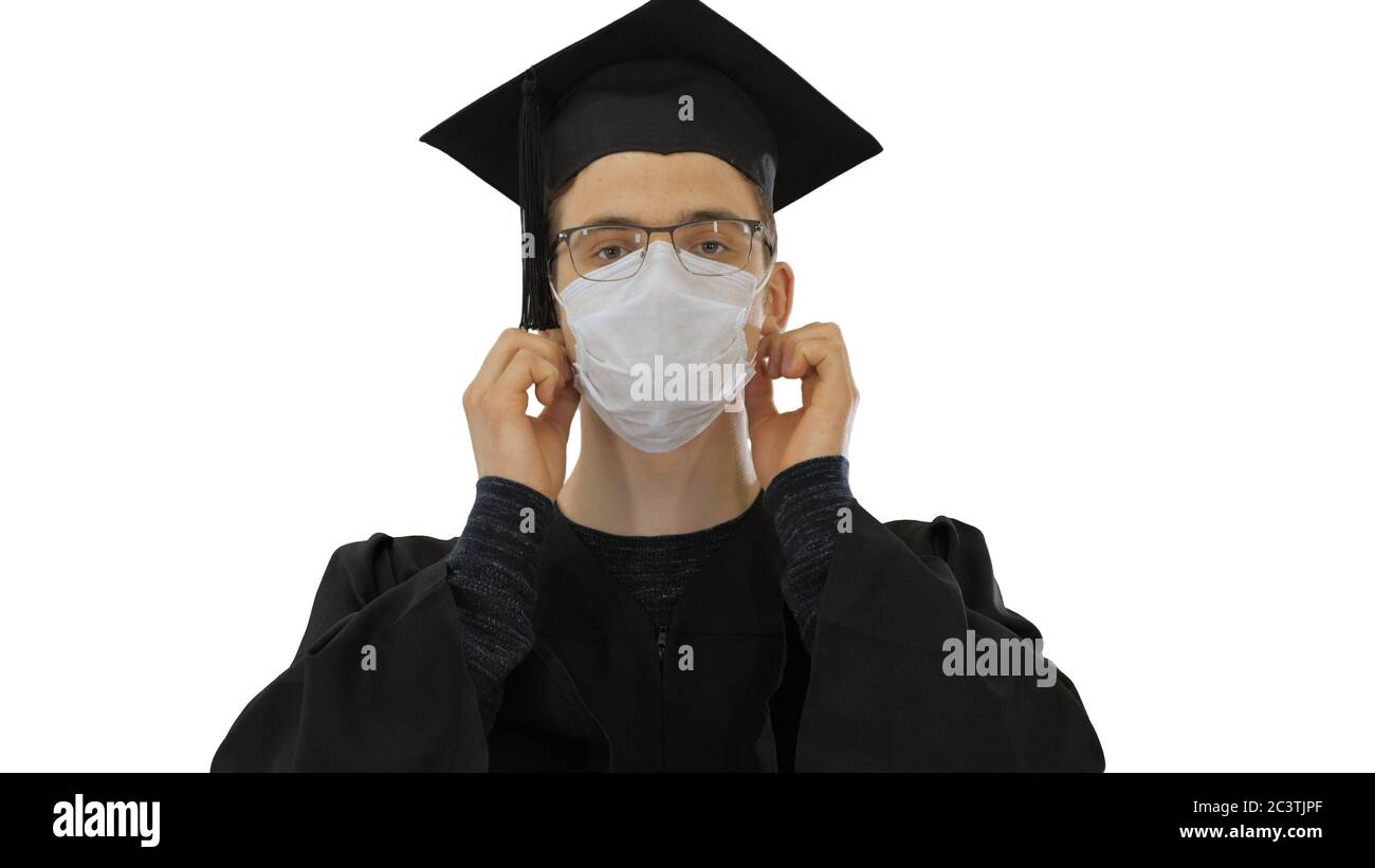 Young man with graduation gown in medical mask on white background ...