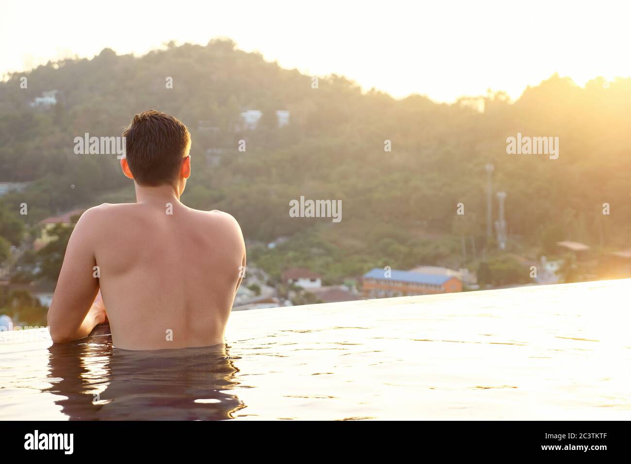 man in hotel outdoor swimming pool looking at pictorial tropical ...