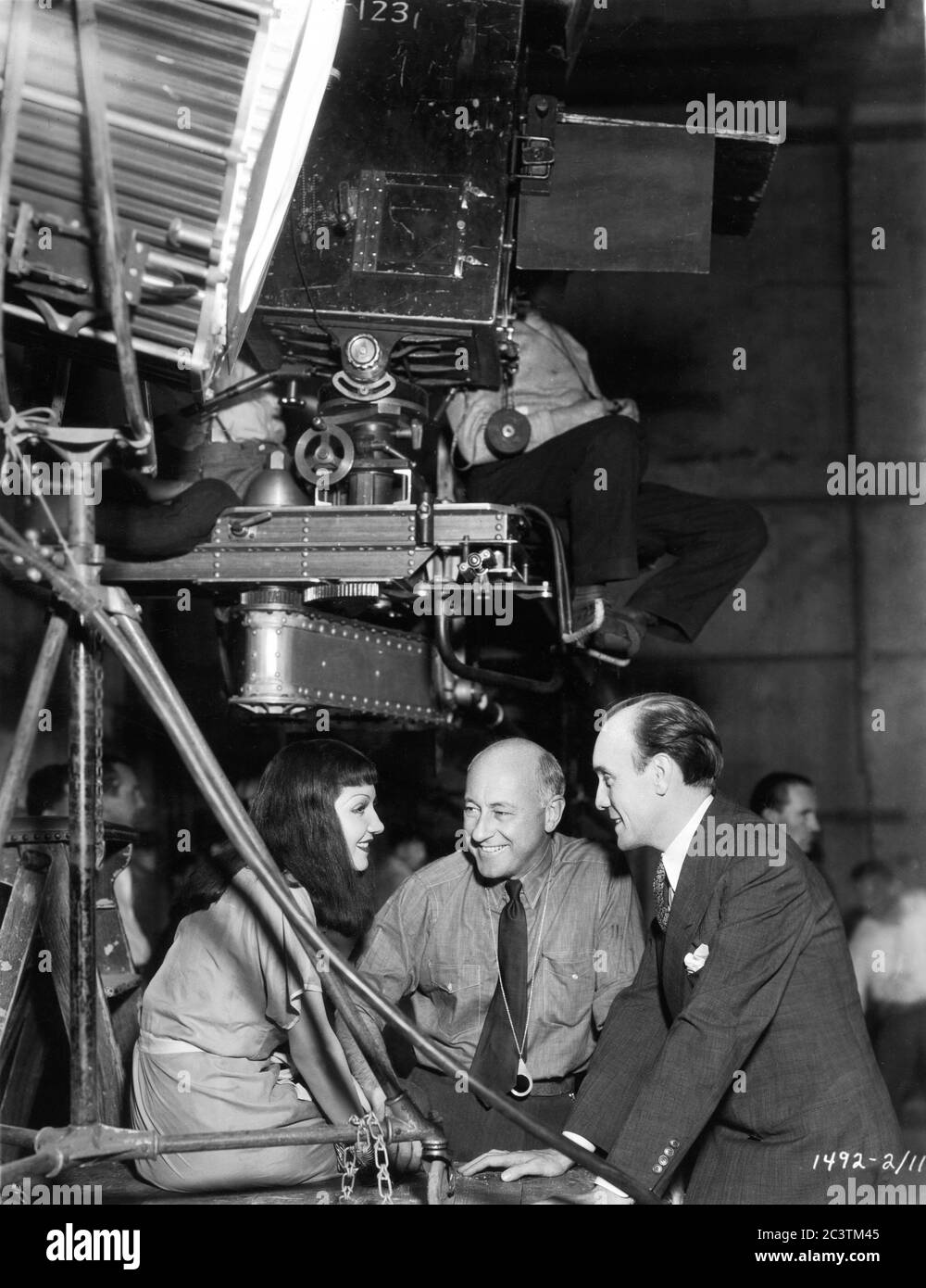 CLAUDETTE COLBERT Director CECIL B. DeMILLE and set visitor theatrical producer EARL CARROLL on ...