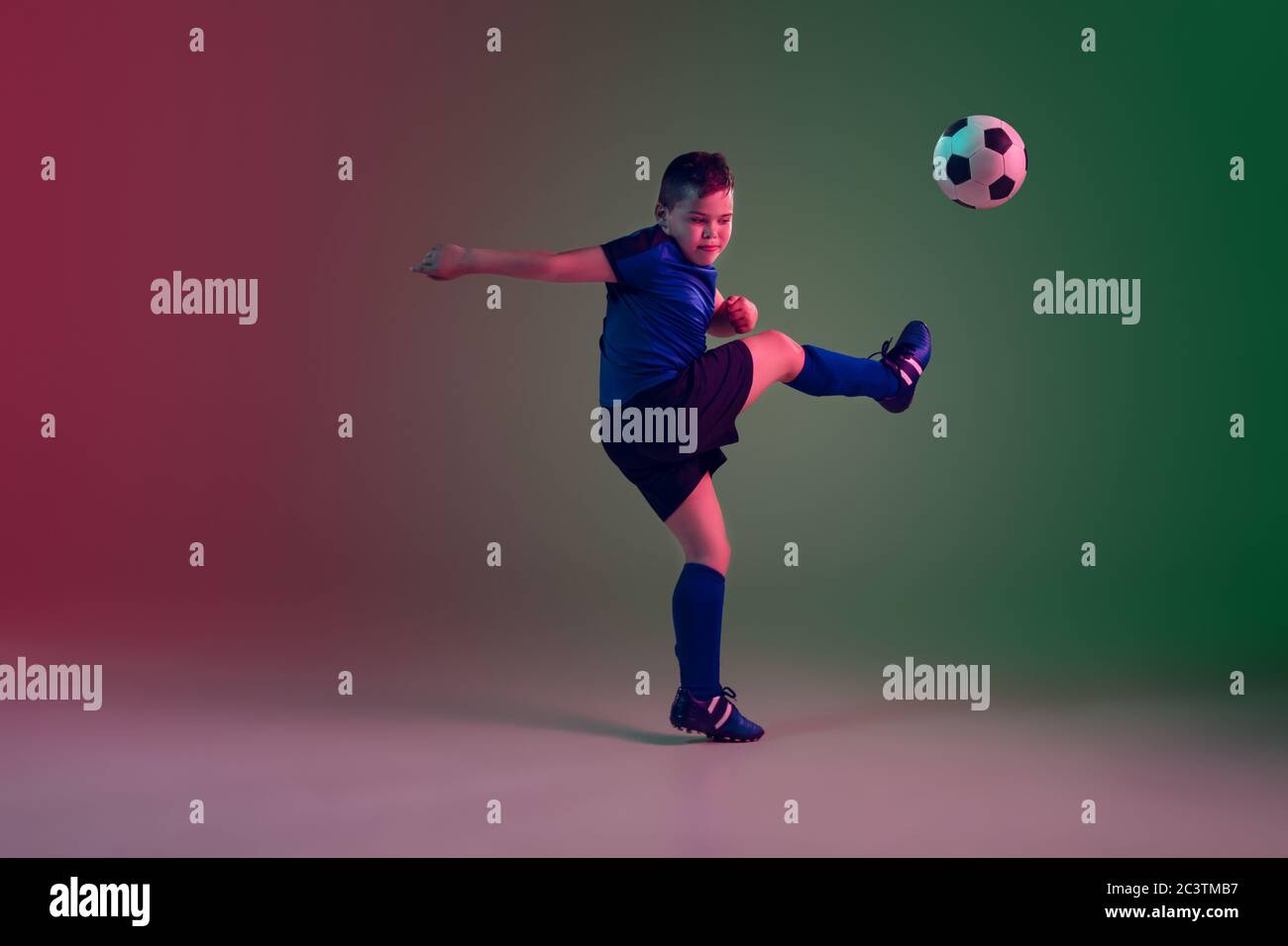 Teen male football or soccer player on gradient background in neon ...