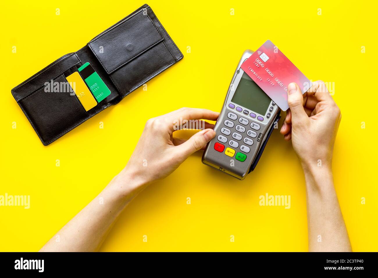 Payment by credit card. Hand hold card near terminal on yellow desk top ...