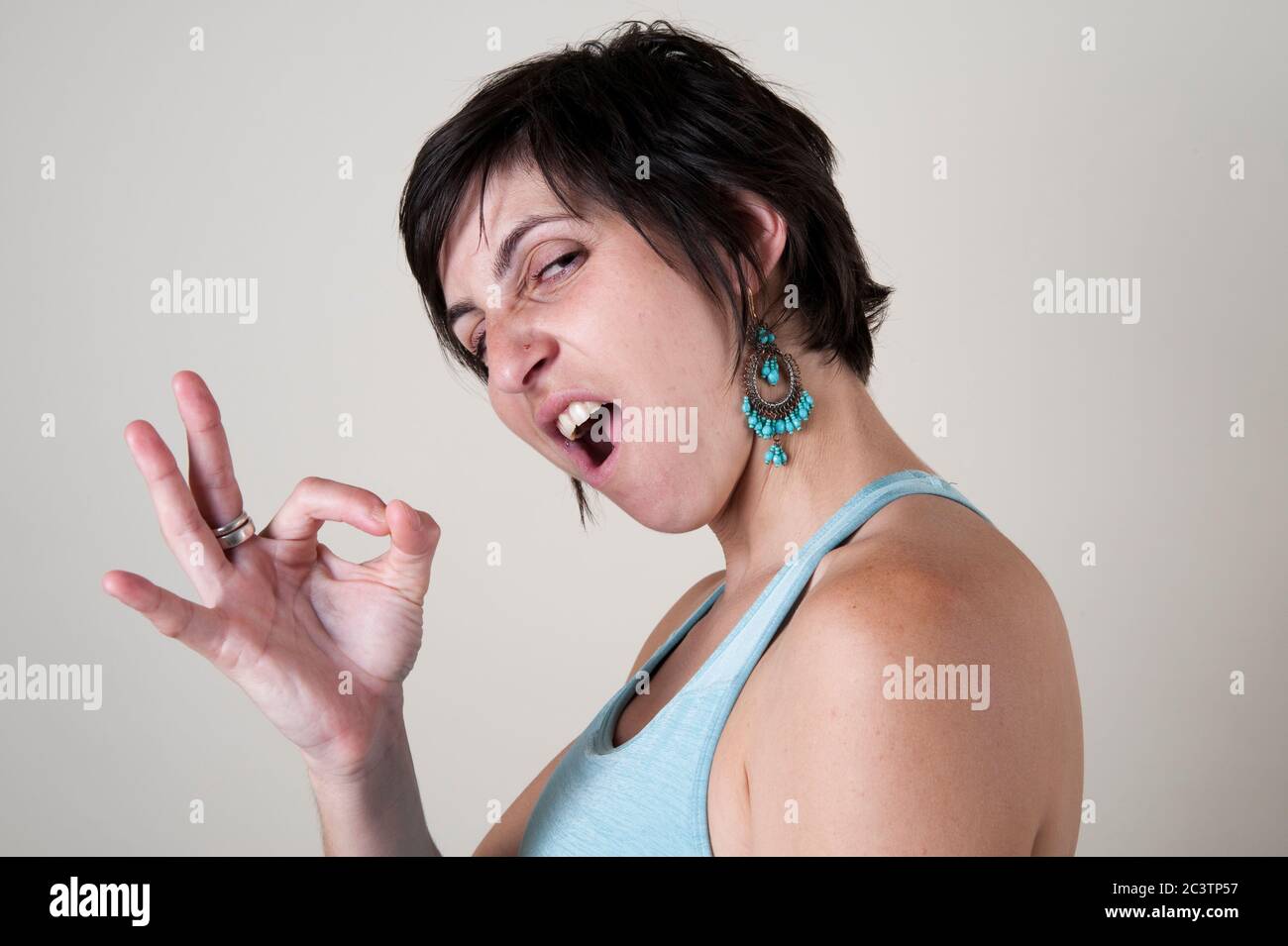 Studio shot of a female model in her 20s doing the OK sign on white ...