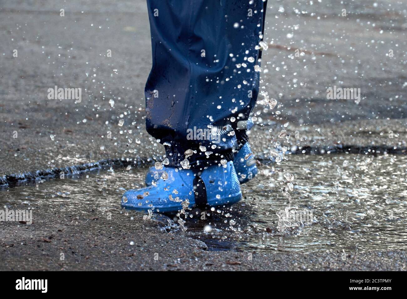 Happy child jumping in puddle in waterproof coat. A boy have fun in the ...