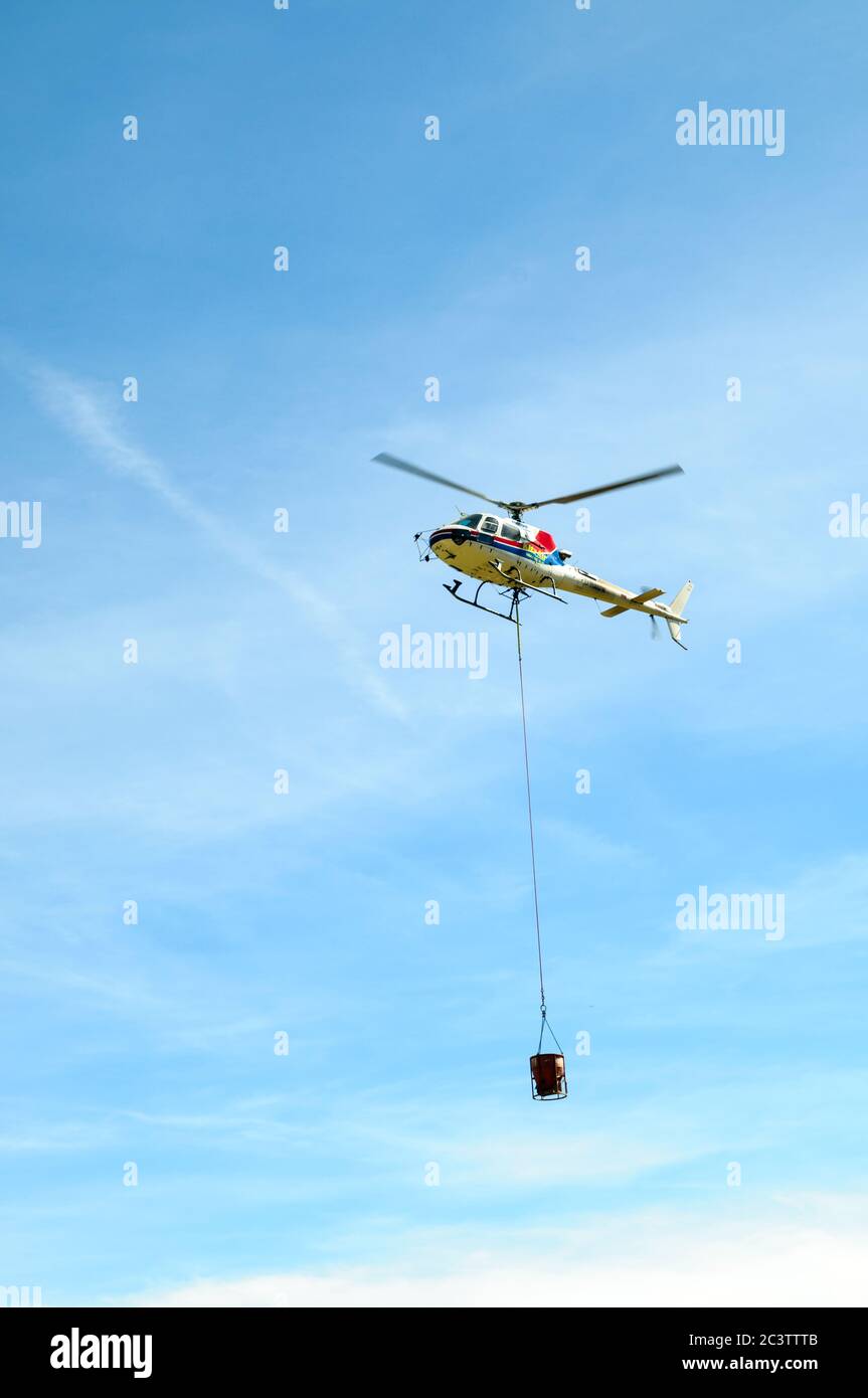 Construction Helicopter carries a load of concrete to pour the ...