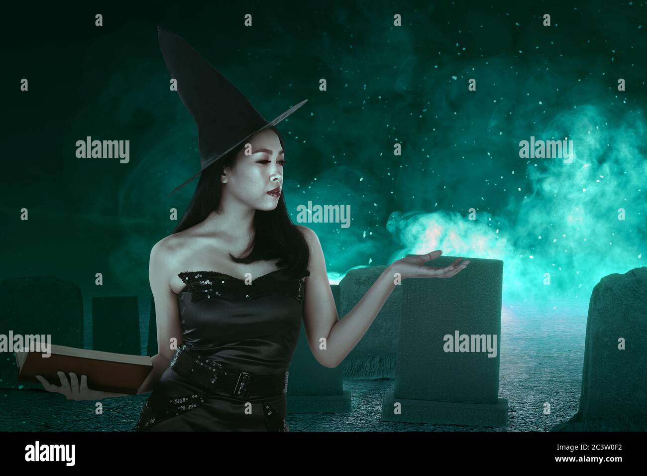 Asian witch woman with spellbook showing magic on her hand on the ...