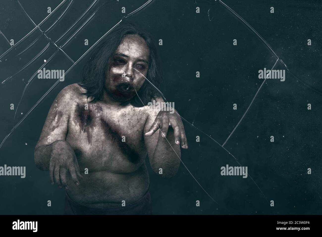 Scary zombie with blood and wound on his body standing in the ...