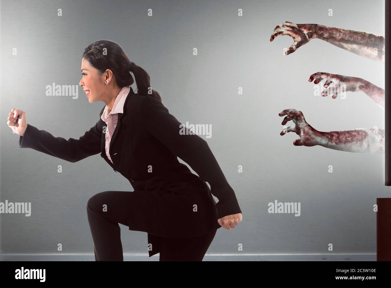 Asian businesswoman running away from zombie's hand coming out of the ...