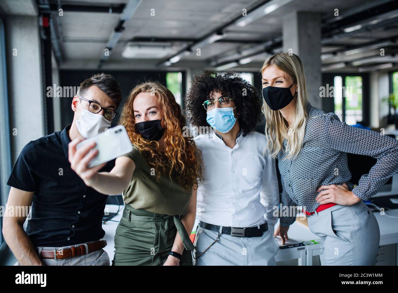 Young people with face masks back at work in office after lockdown ...