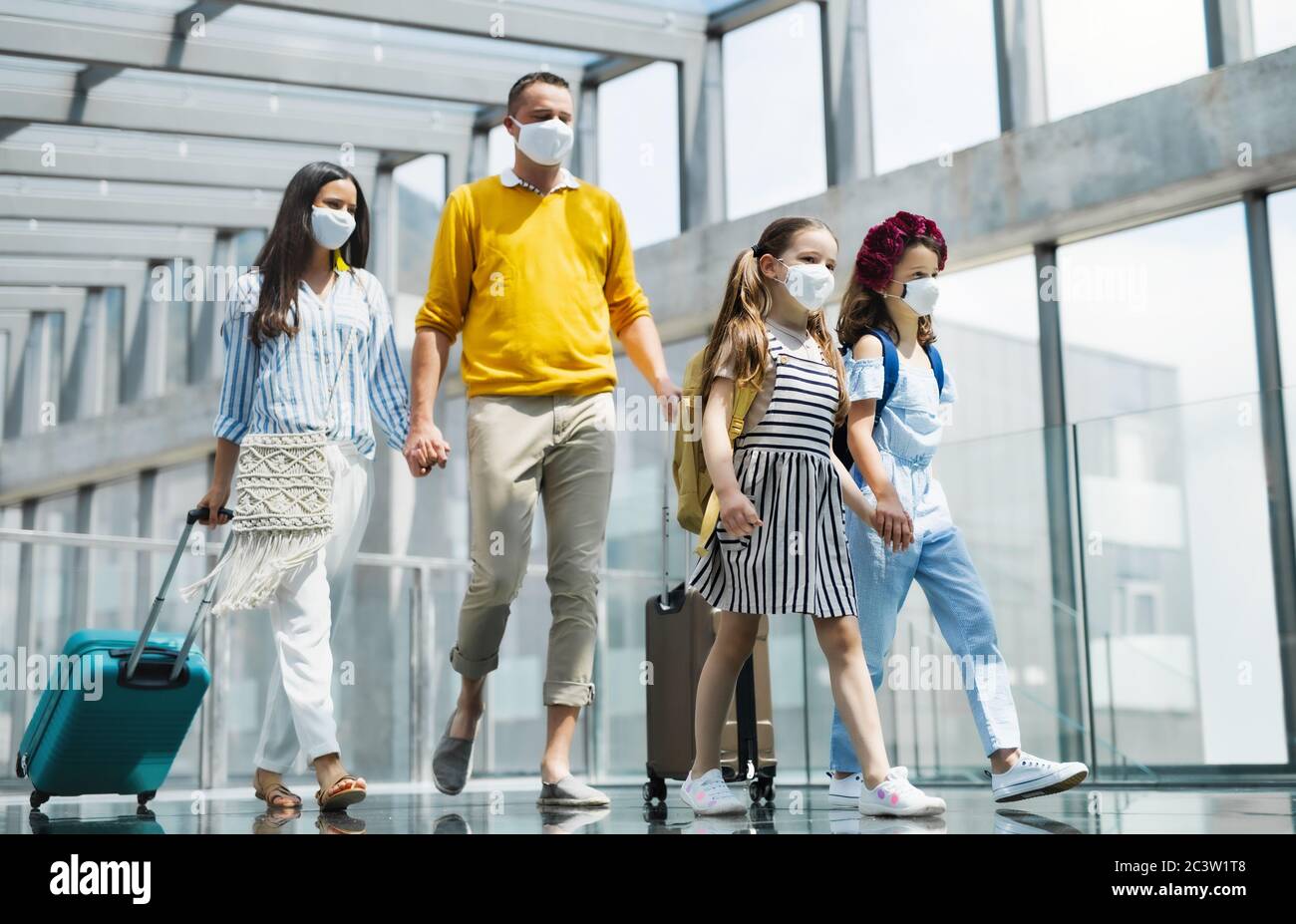 Family with two children going on holiday, wearing face masks at the ...