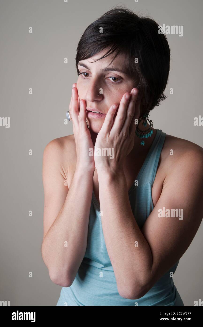 Studio shot of a fearful female model in her 20s on white background ...
