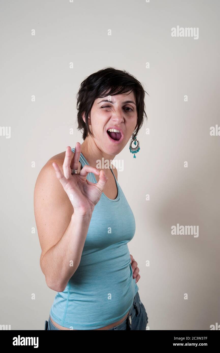 Studio shot of a female model in her 20s doing the OK sign on white ...