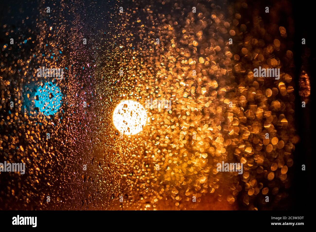 Raindrops on a window with the city lights at night, abstract blurred ...