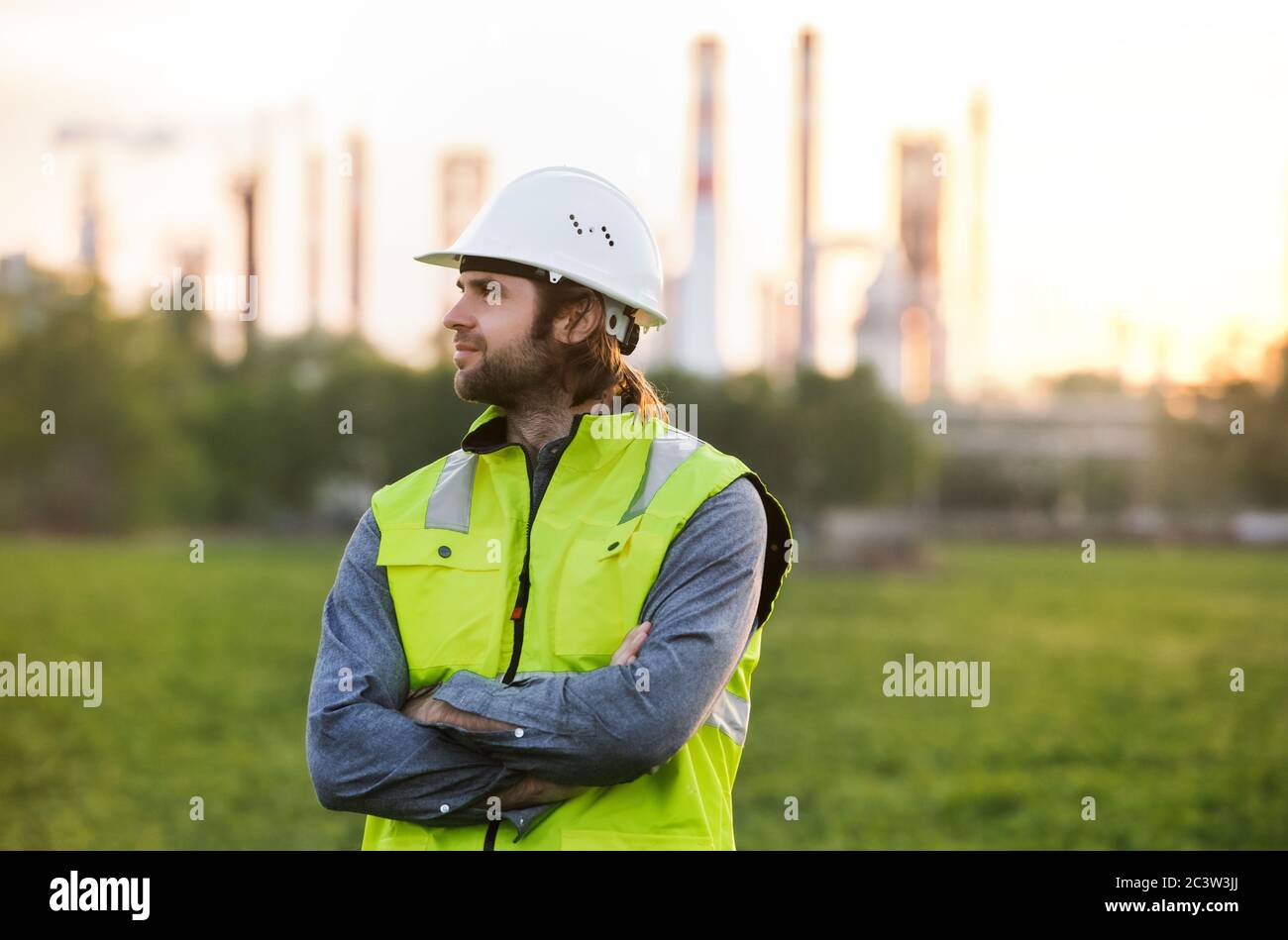 Young engineer standing outdoors by oil refinery, arms crossed Stock ...