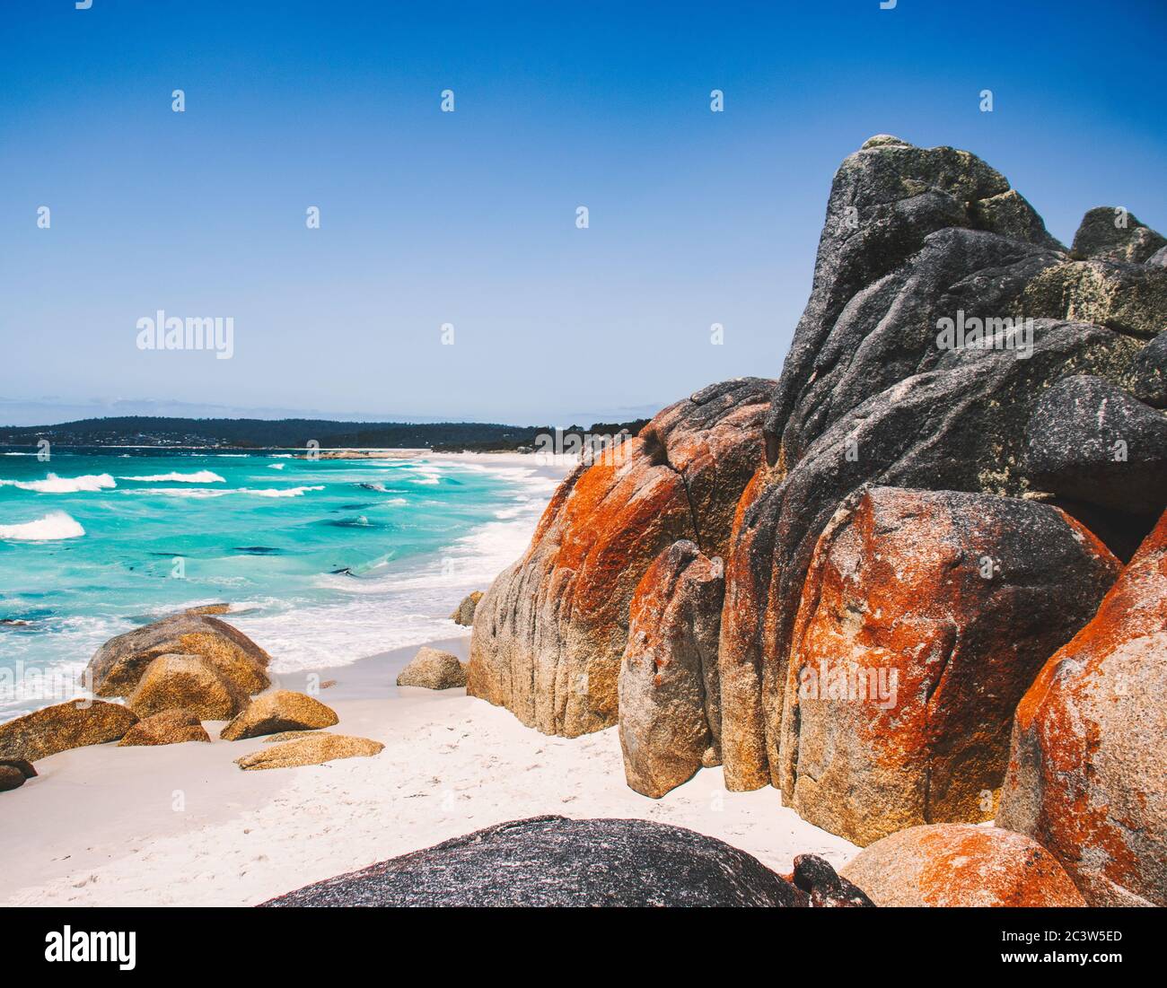 Red Rock Boulders on white sand next to the blue ocean Stock Photo - Alamy