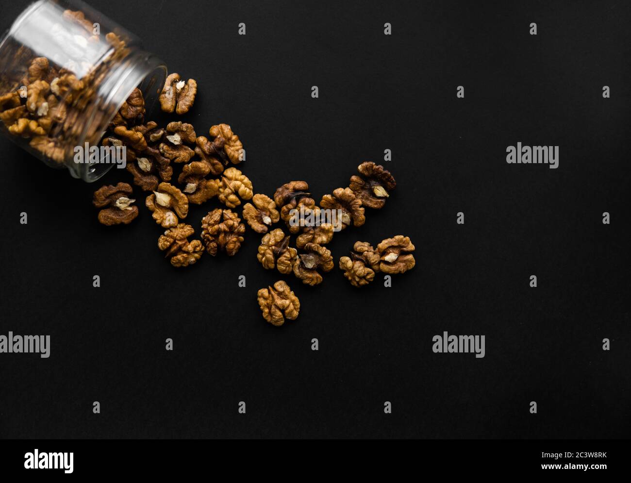Walnut scattered on the black table from a jar. Walnut is a healthy ...