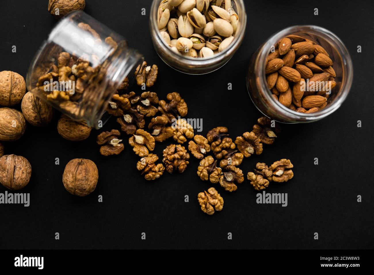 Walnut scattered on the black table from a jar. Walnut is a healthy ...