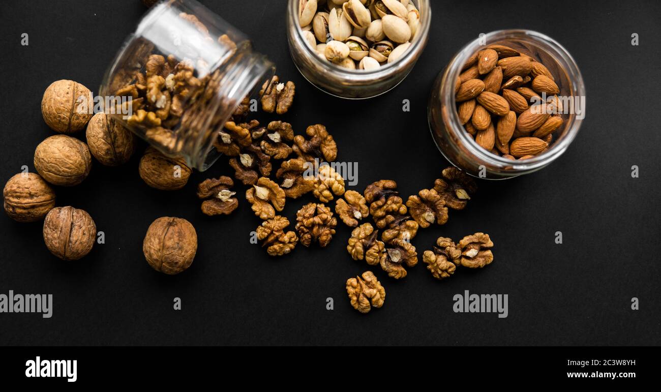 Walnut scattered on the black table from a jar. Walnut is a healthy ...