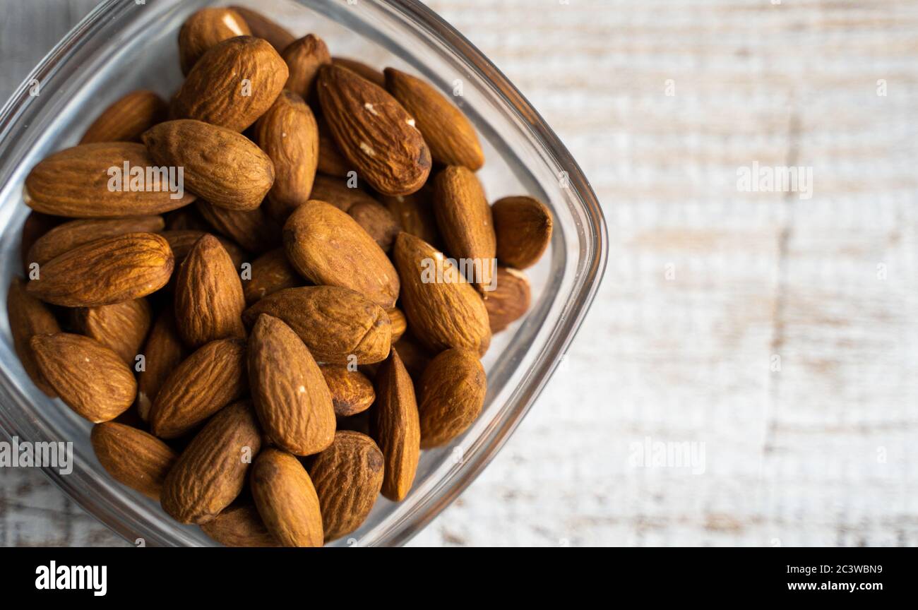 Almonds in a small plate on a vintage wooden table. Almond is a healthy ...