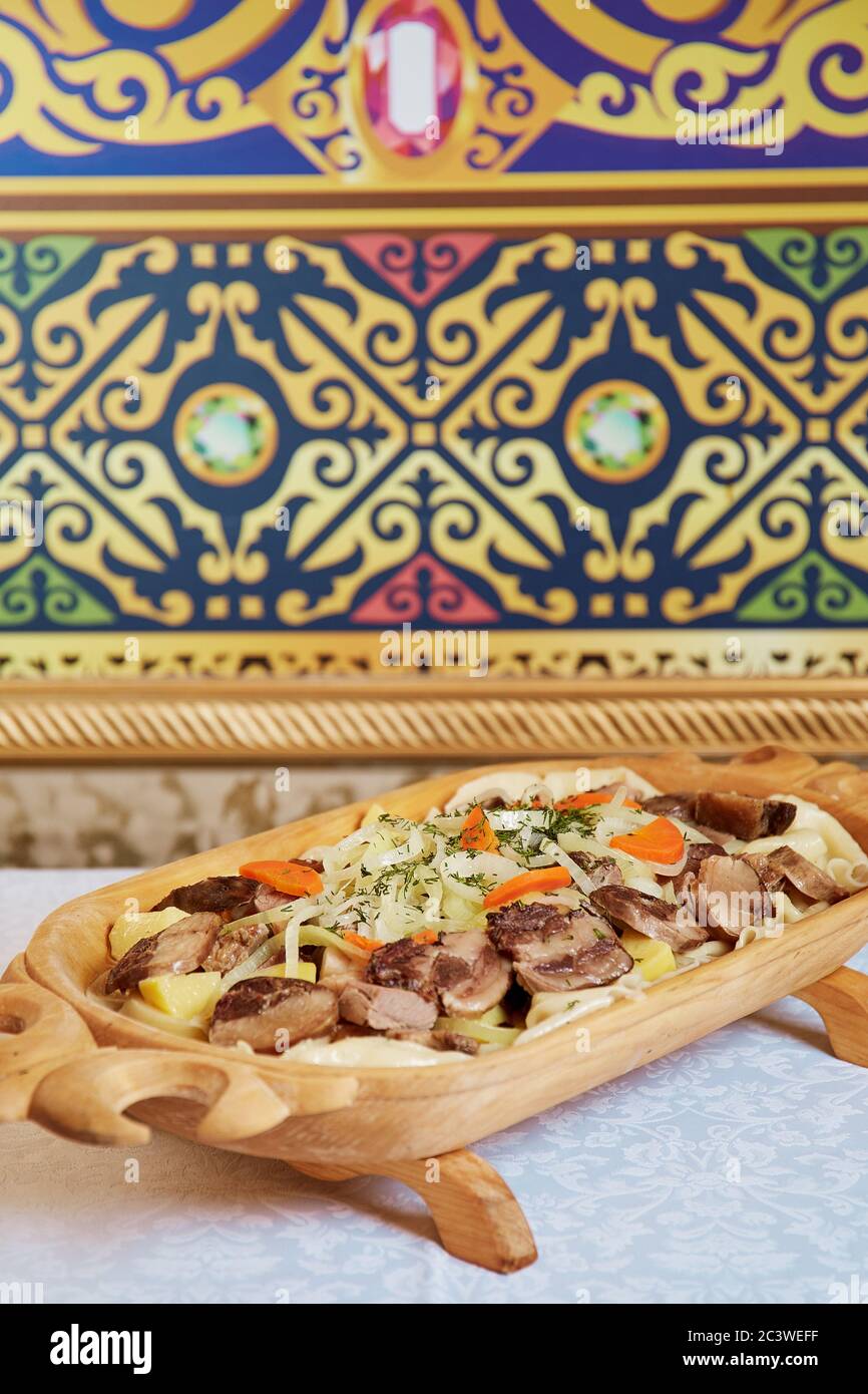 Nationally Kazakh dish beshbarkak in wooden utensils. Background with ...