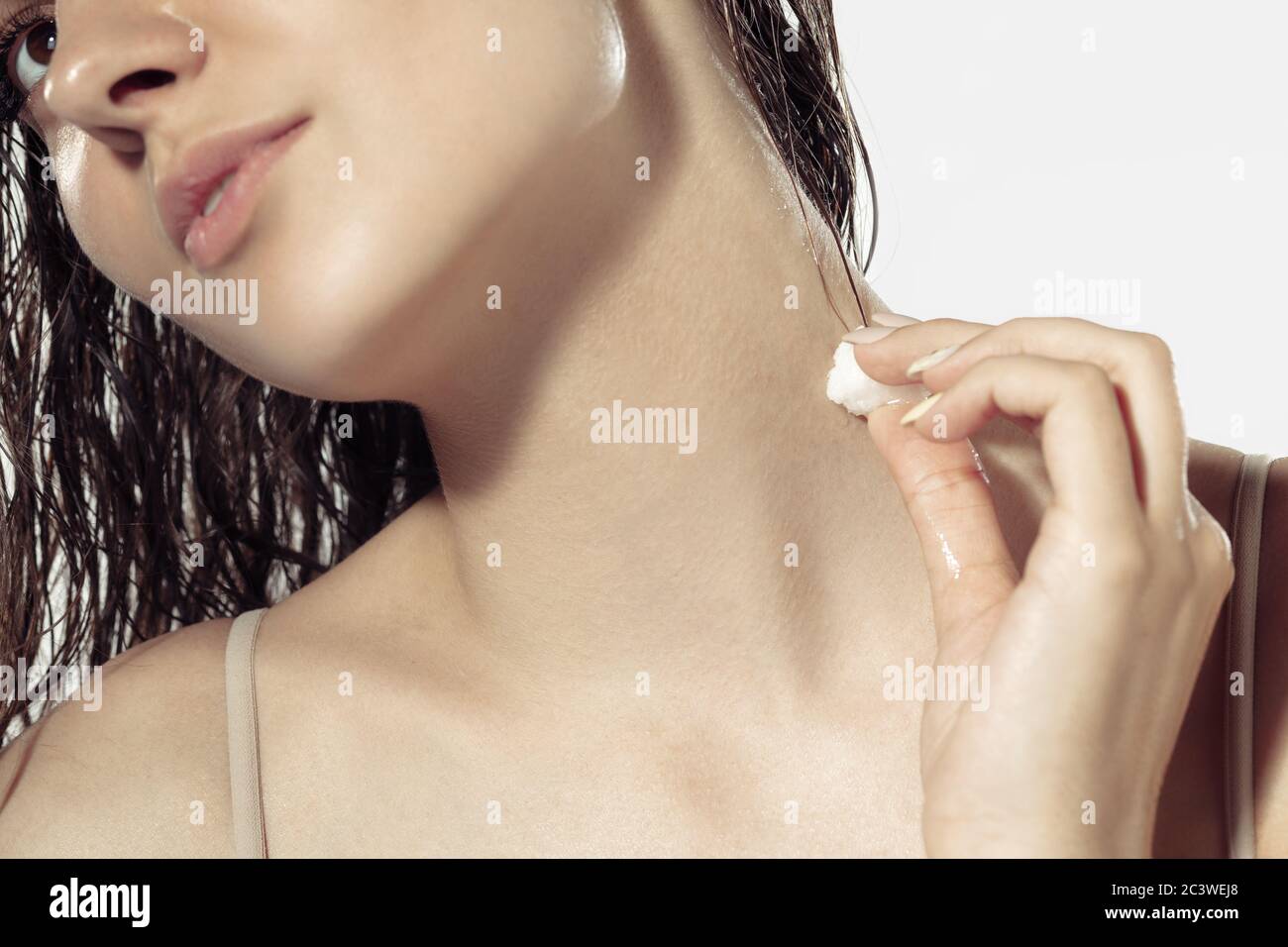 Close up beautiful young woman scrabing skin on white studio background ...